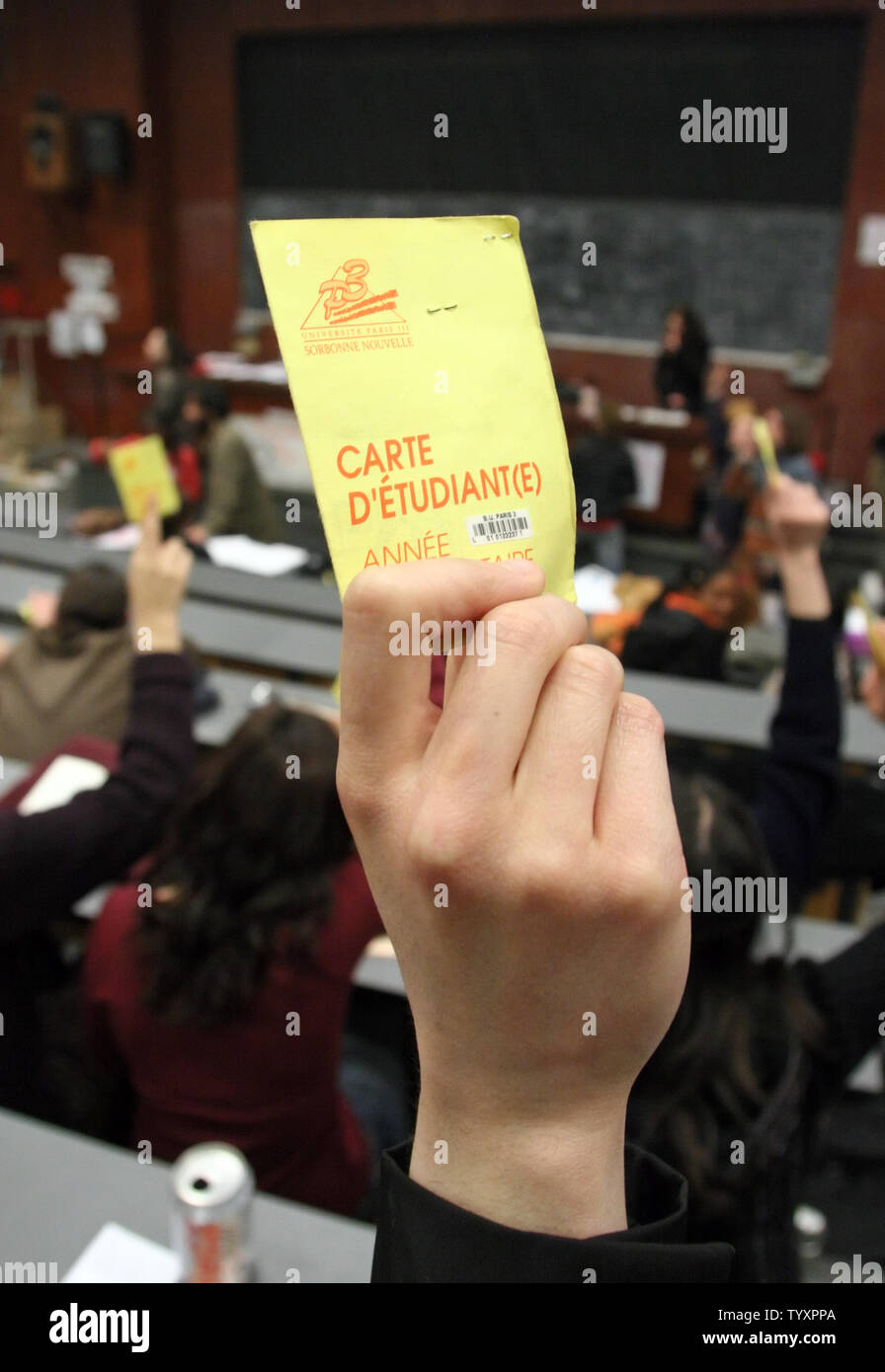 Students hold up their student ID cards to vote during a general ...