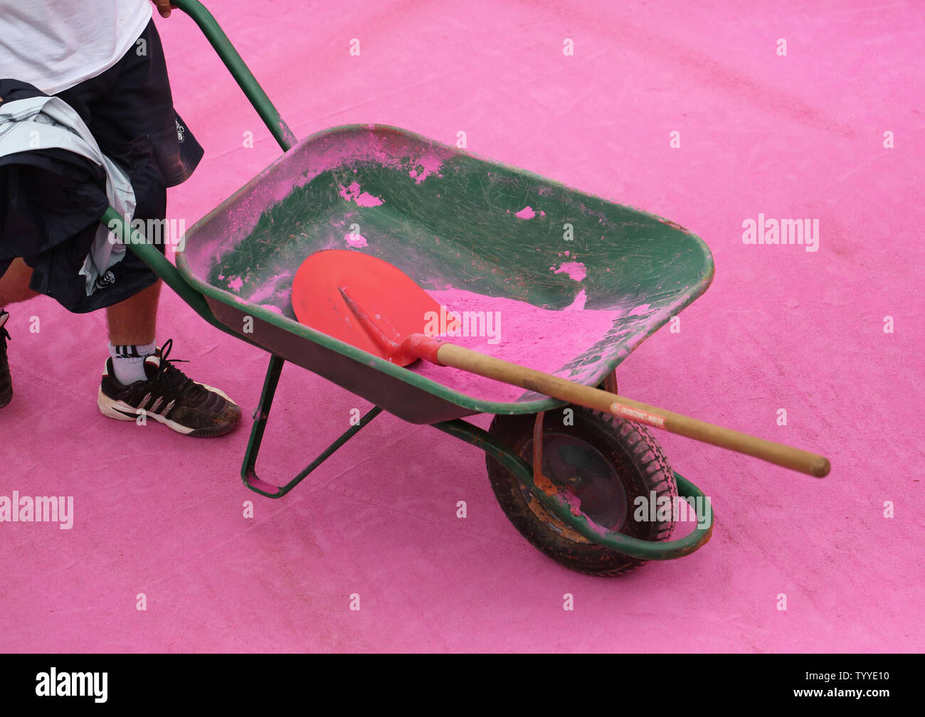 A worker rolls a wheelbarrow on Court 1 which was resurfaced with pink ...