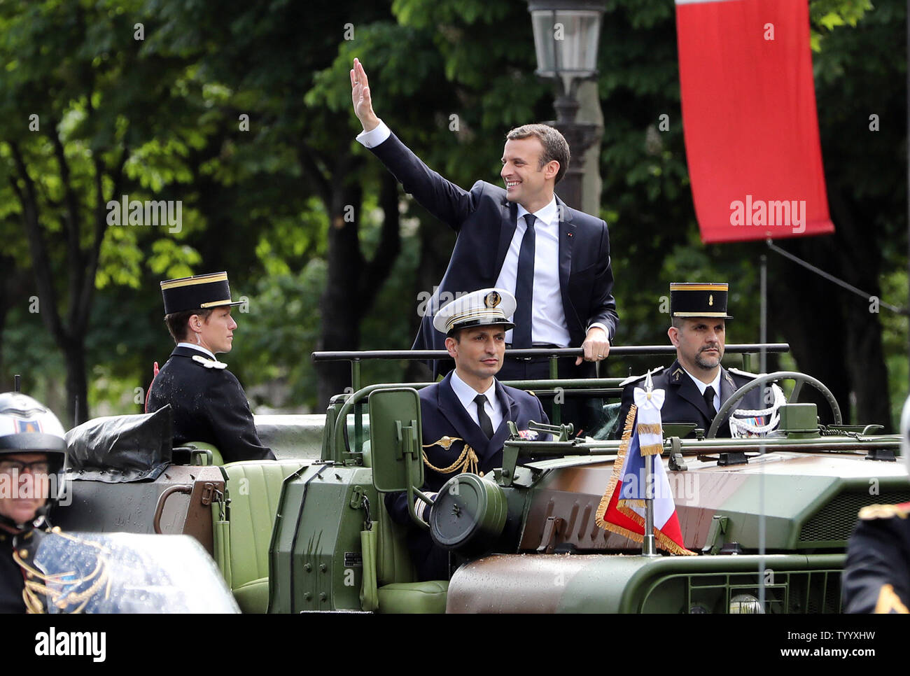 France's new president Emmanuel Macron waves from a command car as he ...