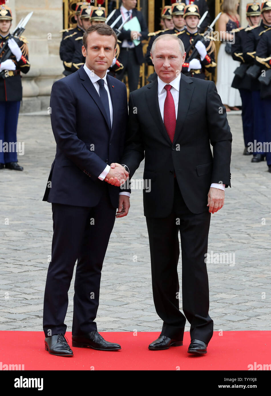 French President Emmanuel Macron (L) greets his Russian counterpart ...