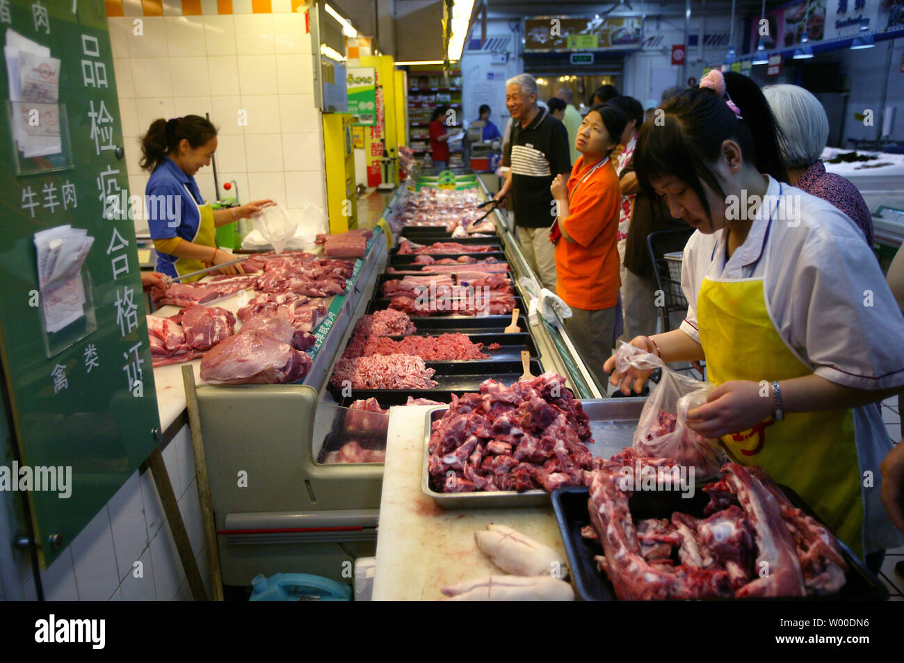 Chinese shoppers shop for freshly slaughtered pig meat at a butcher ...