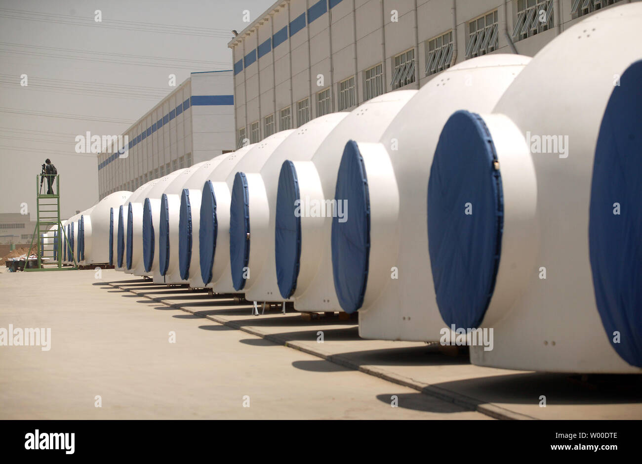 Parts of massive wind turbines sit outside a factory as reporters tour ...