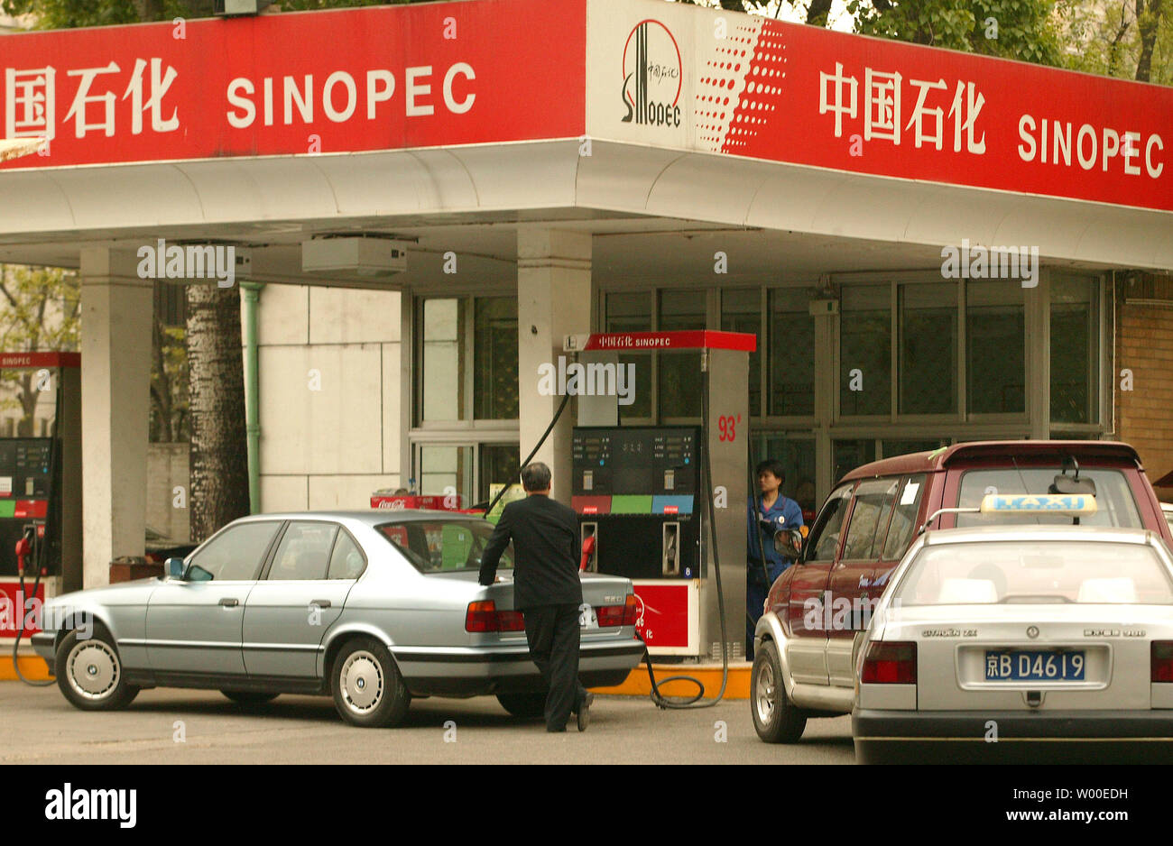 A man fills his tank as cars wait in line at a gas station in downtown ...