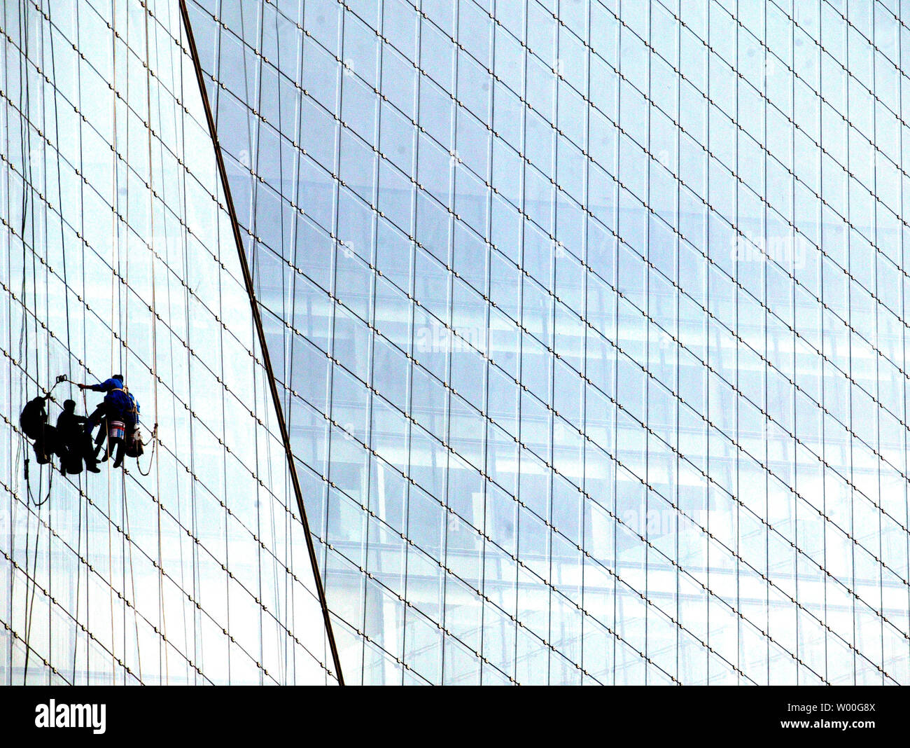 Two window washers clean the massive glass exterior of an office ...
