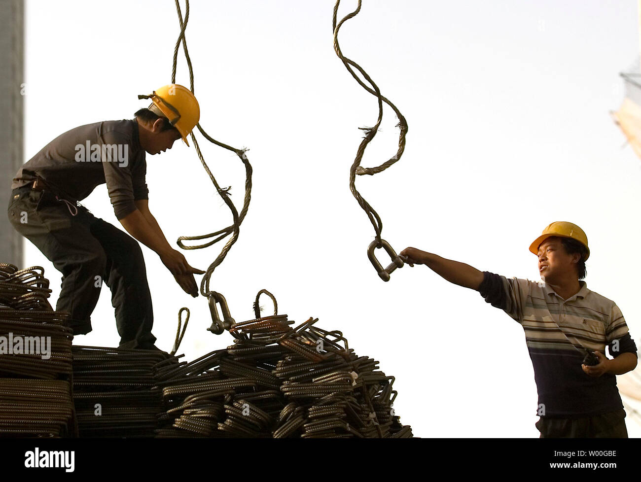 Chinese workers grab hold of steel cables that they'll attach to stacks ...