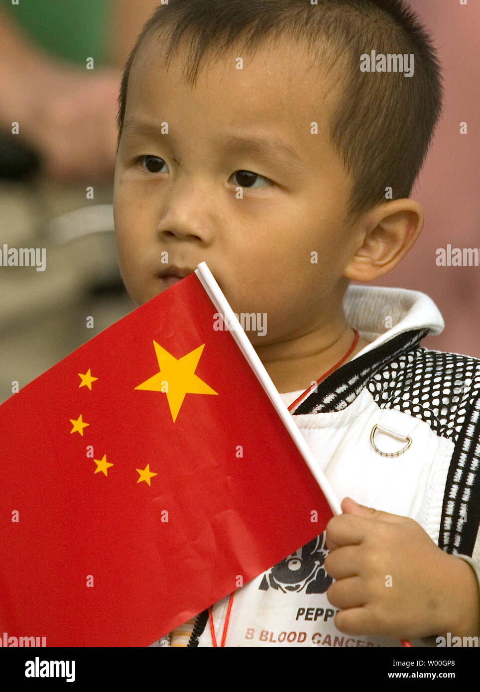 A young boy holds a plastic Chinese flag as thousands of Chinese ...
