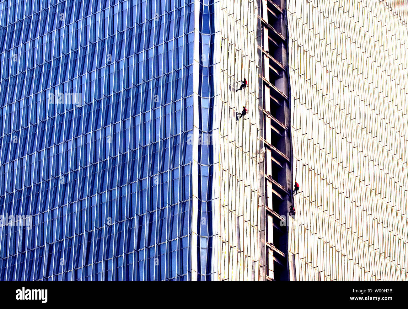 Chinese workers dangle on rope chairs as they attach light tubes to the ...