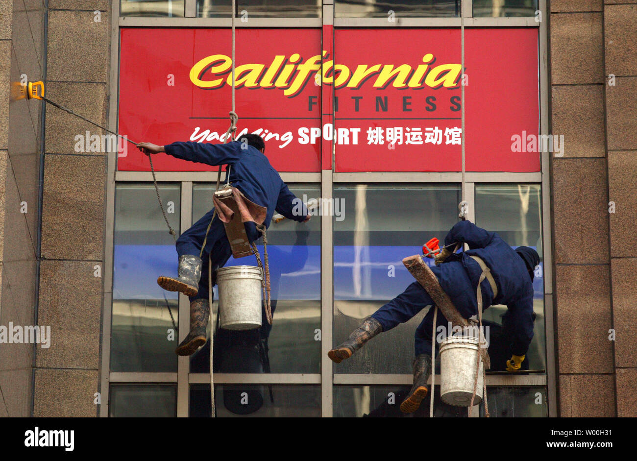 Two Chinese window washers hang on ropes as they clean the exterior of ...