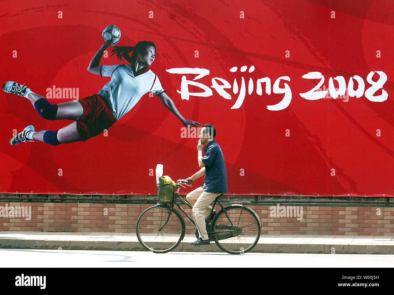 A Chinese man bicycles past an Olympic billboard, one of thousands ...