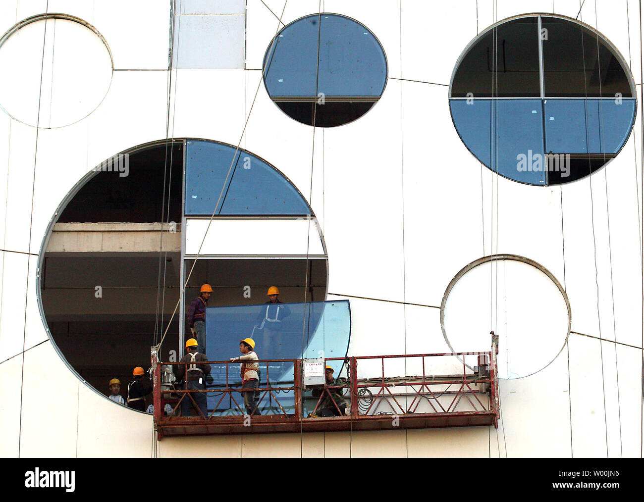Chinese construction workers install glass windows on a new, upscale ...