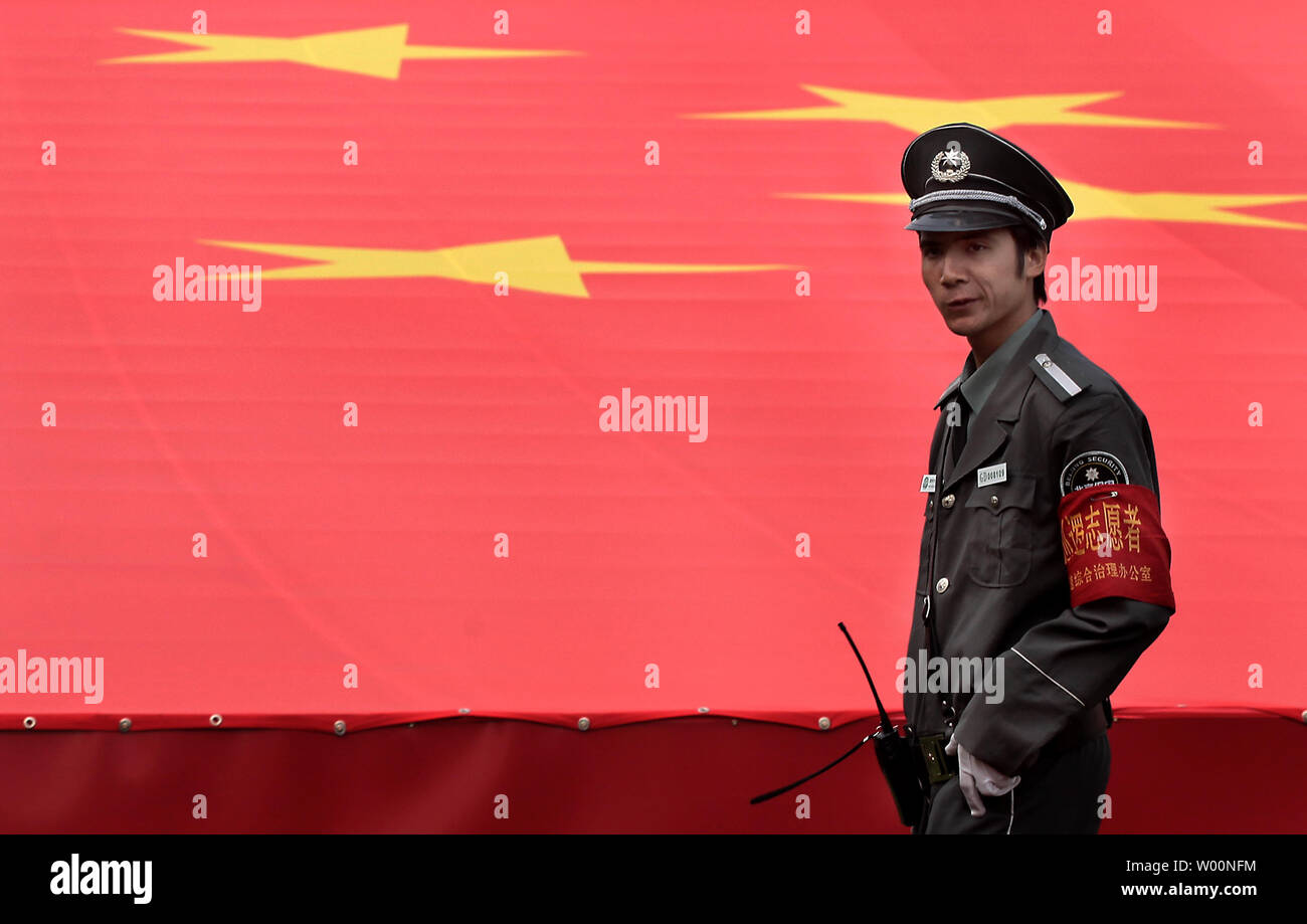 A Chinese security guard stands in front of a giant Chinese national ...