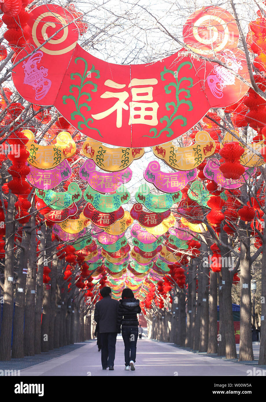 Chinese stroll under traditional red lanterns and 'good luck' banners ...