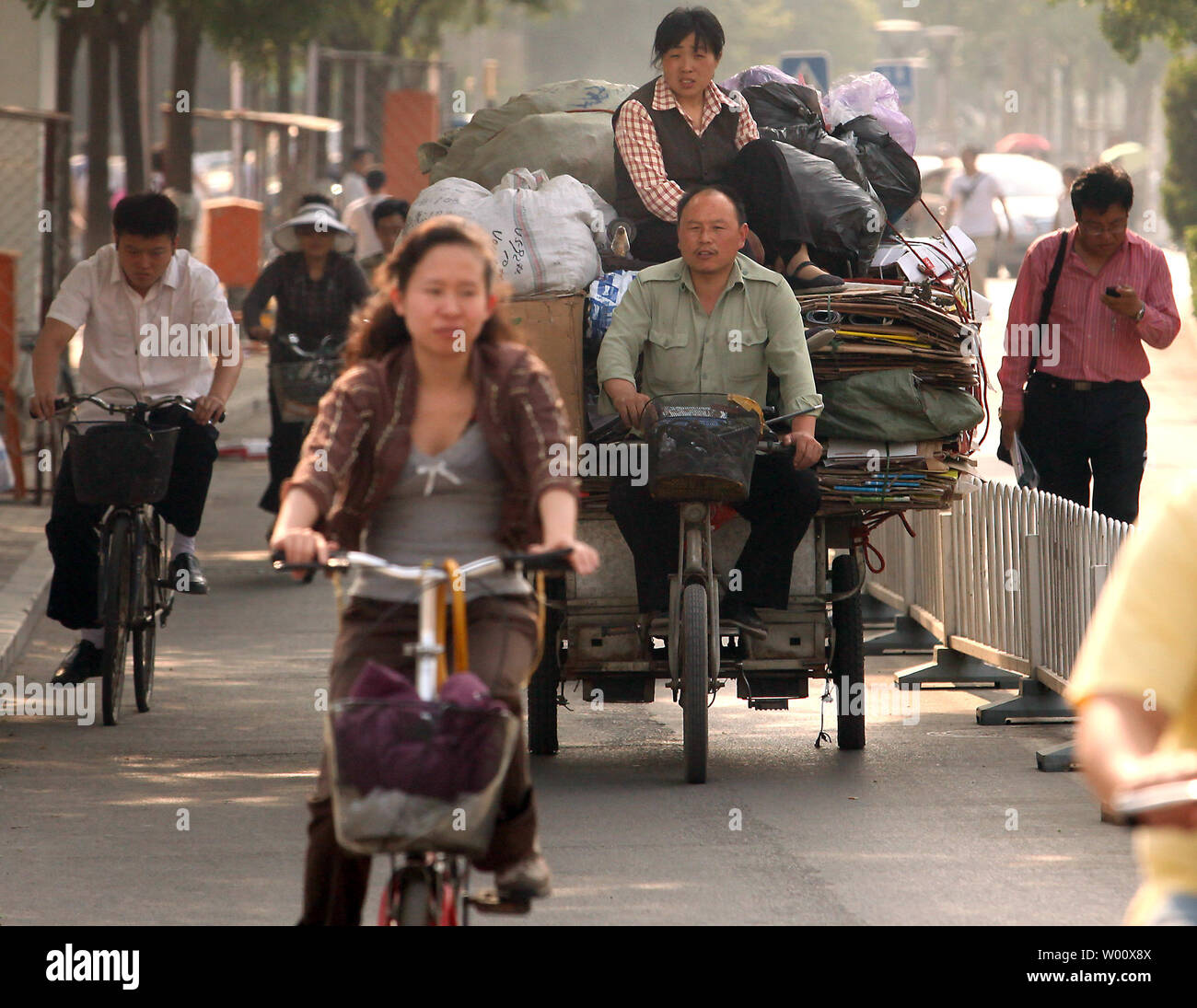 A migrant Chinese man hauls his wife and the days bounty of recyclable ...