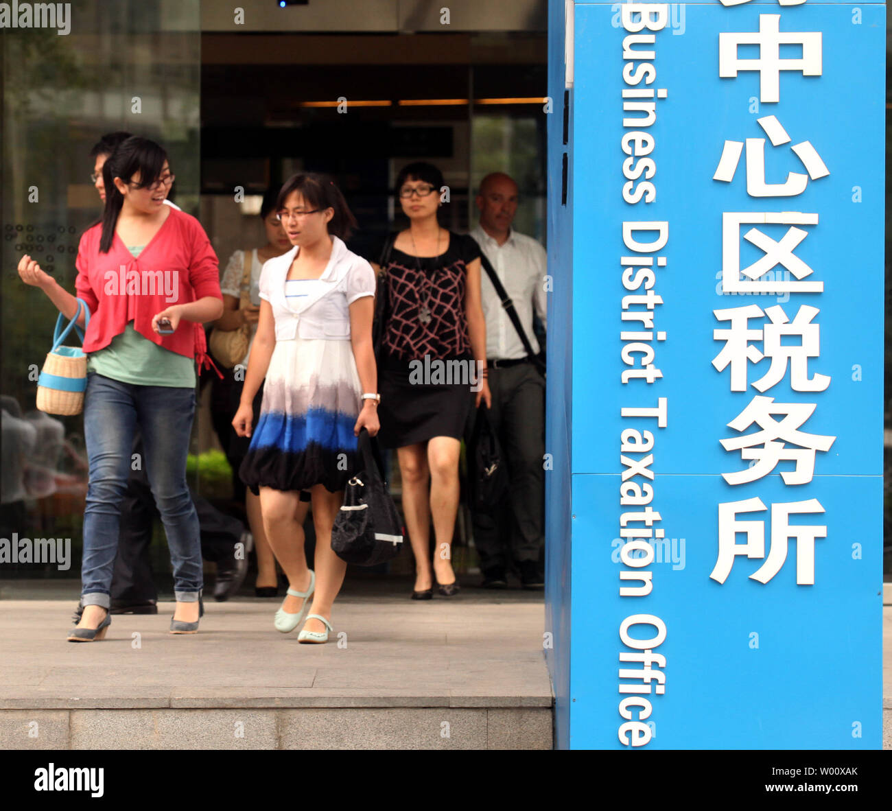 Chinese walk out of a tax collection office in downtown Beijing on June ...