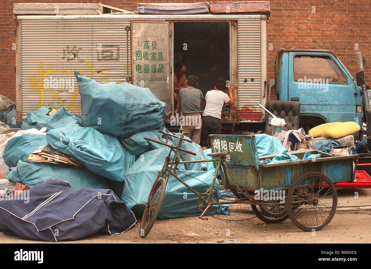 Chinese migrant workers negotiate with a recyclable-trash collector on ...