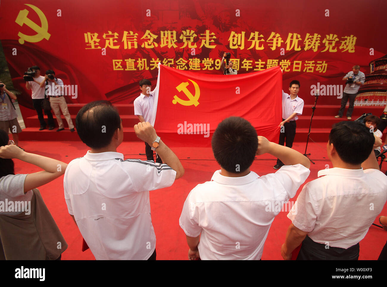 Chinese salute the Communist Party flag during an outdoor celebration ...