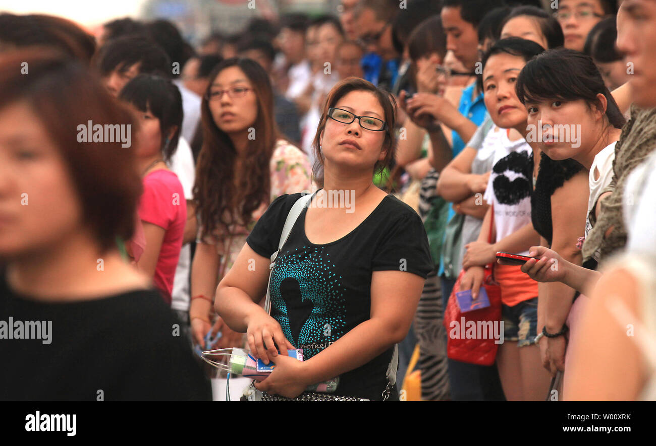 Eager commuters wait for their bus at a crowded bus stop in downtown ...