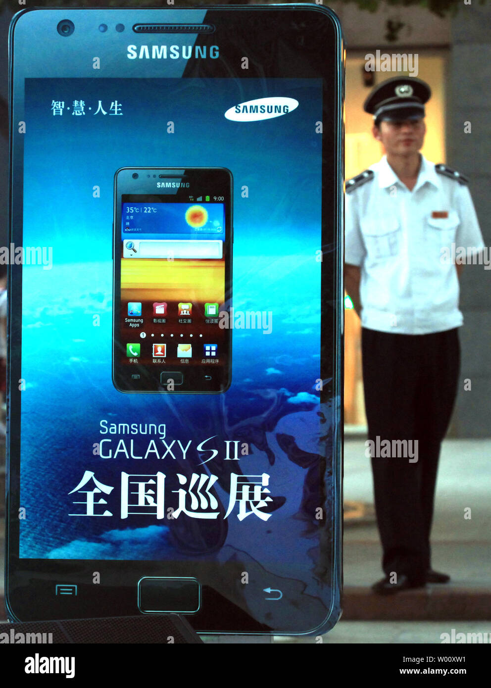 A Chinese security guard stands next to a large display of Samsung's ...
