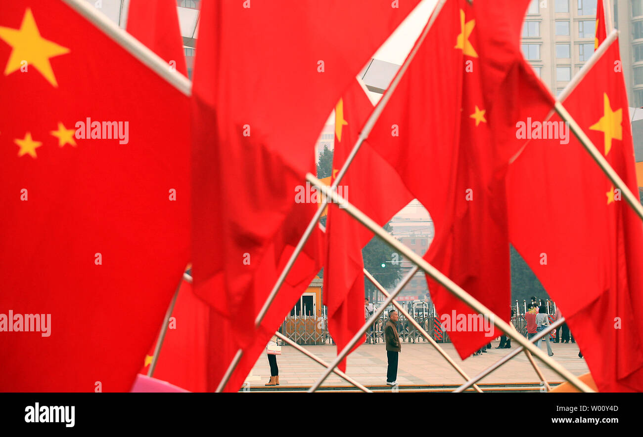 A man stands in front of a flurry of Chinese national flags on display ...