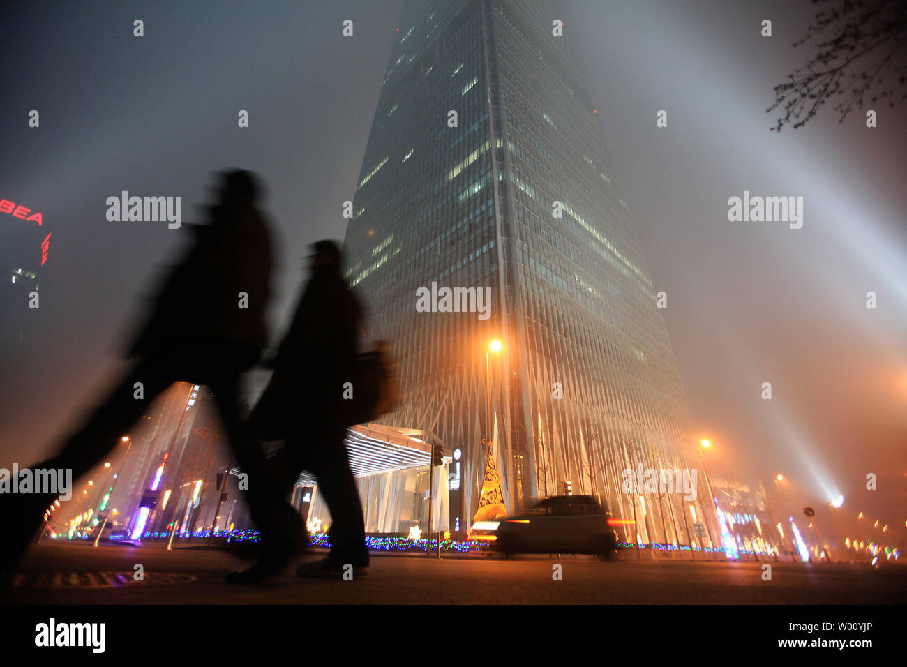 Chinese walk past Beijing's tallest skyscraper, shrouded in a thick ...