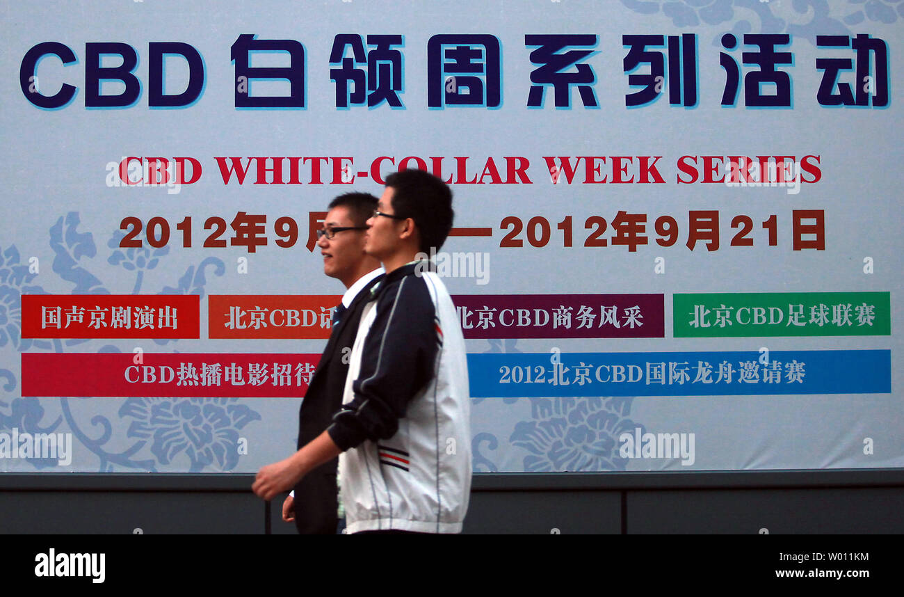 Chinese men walk past an advertisement for a trade fair promoting the ...