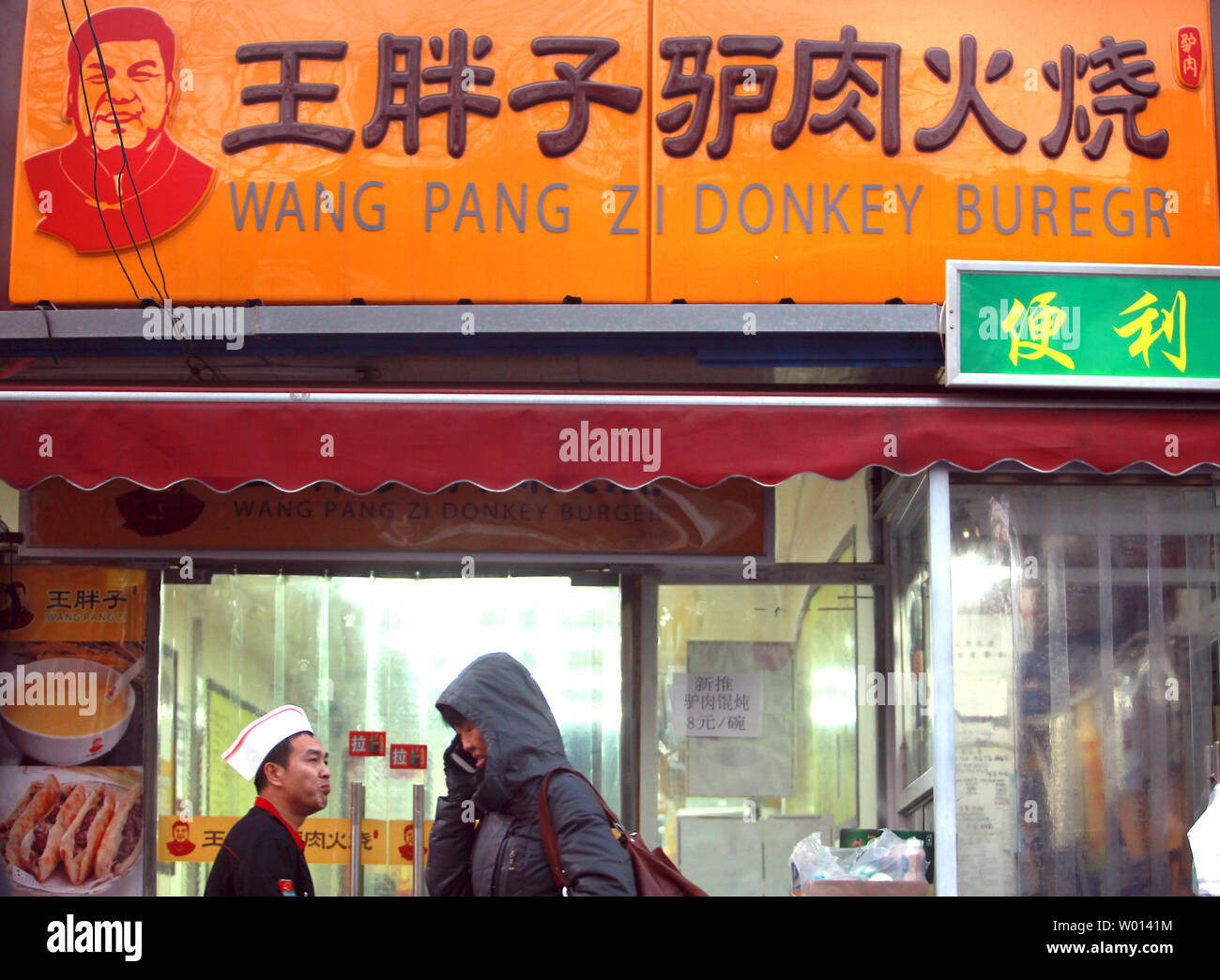 Chinese walk past a popular restaurant that specializes in donkey meat ...