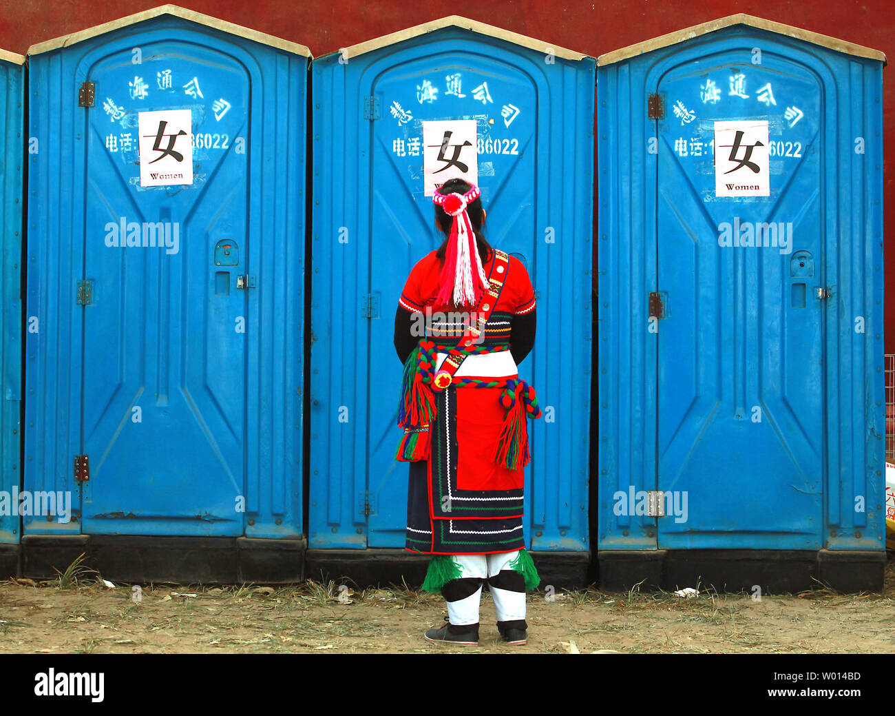 A Chinese ethnic minority woman waits to use a toilet at a temple fair ...