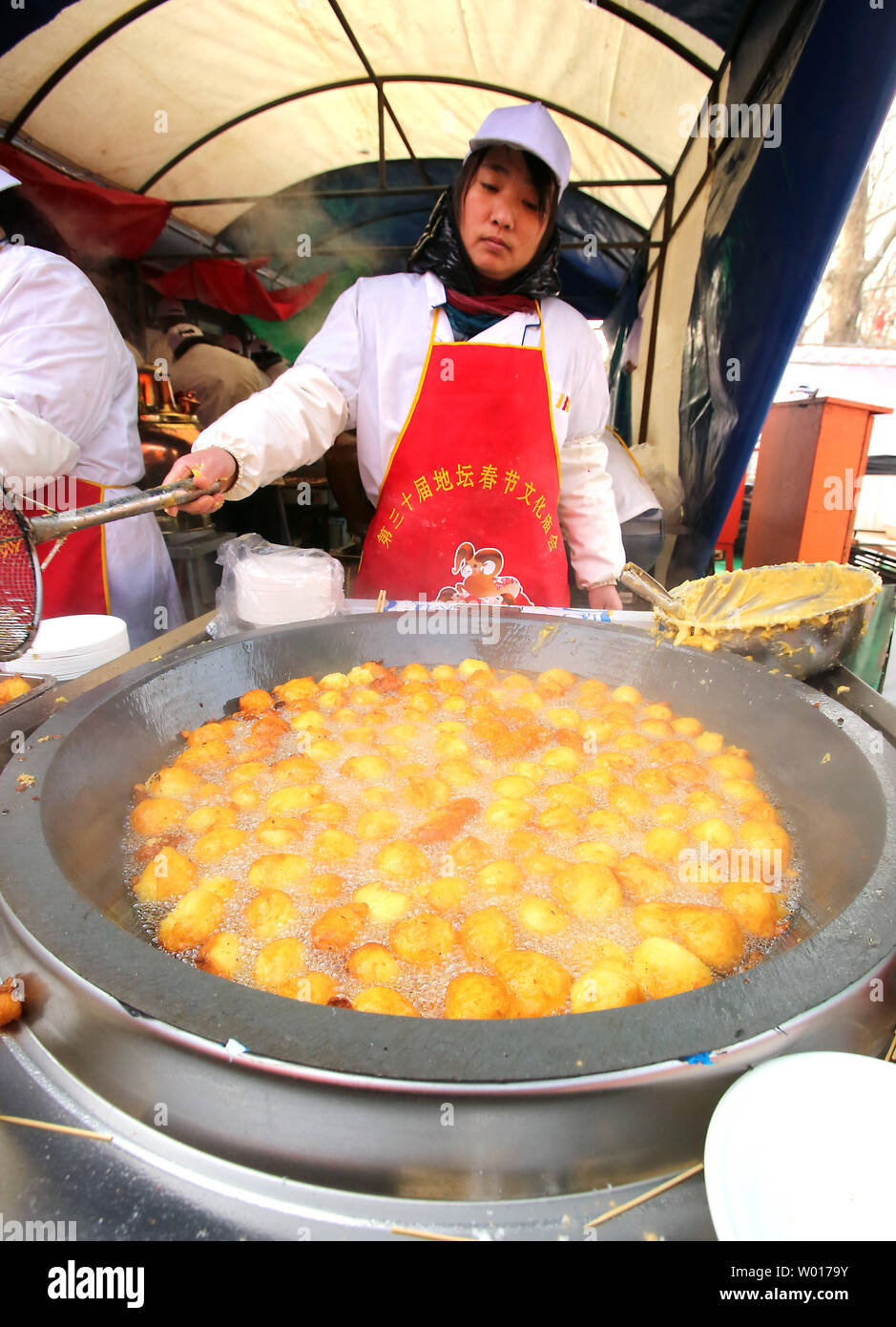 A Chinese cook fries dough balls at a food stand as the Chinese Spring ...