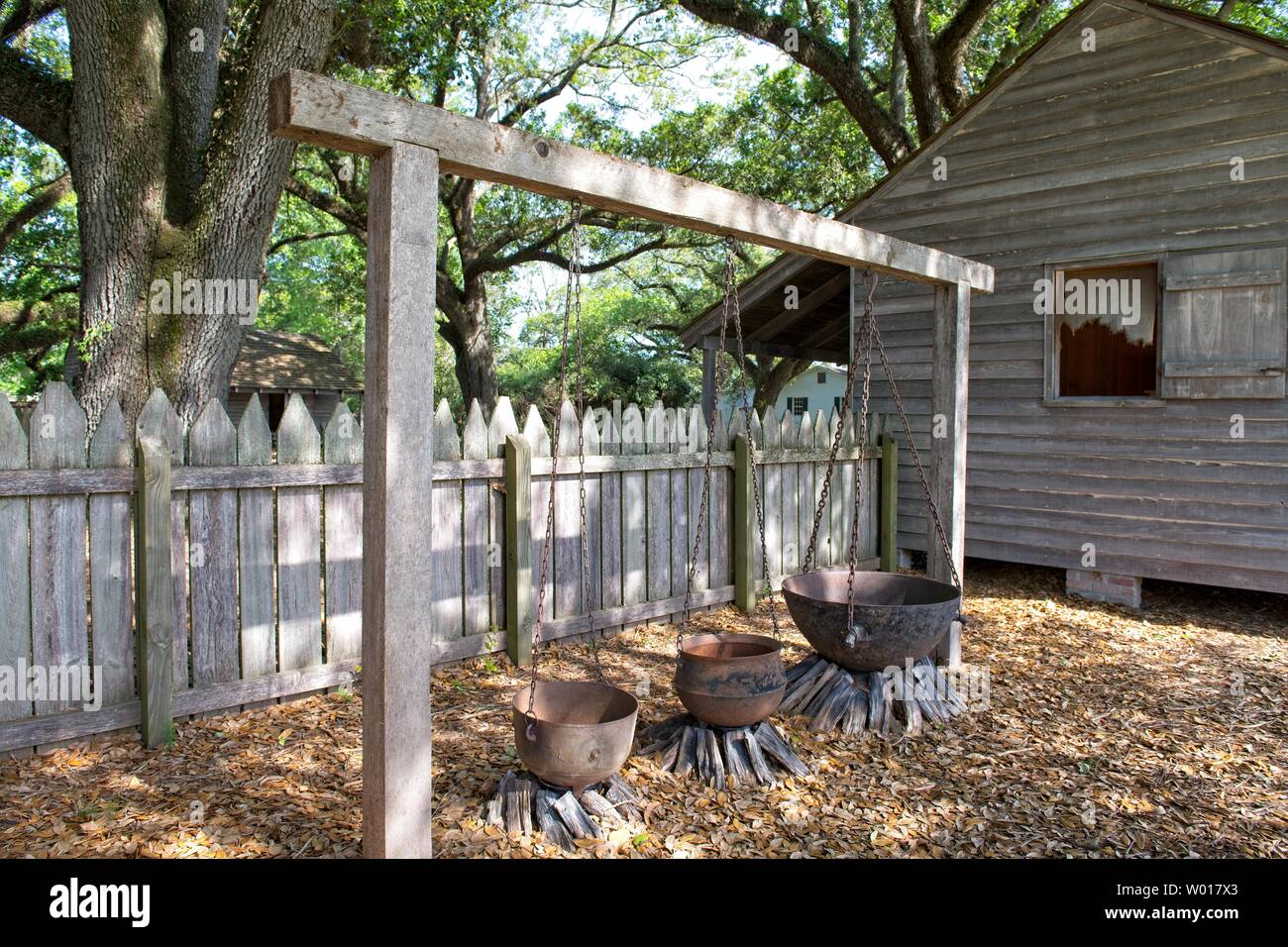 Rusty kettles hang from a wooden structure near an old farmhouse Stock ...