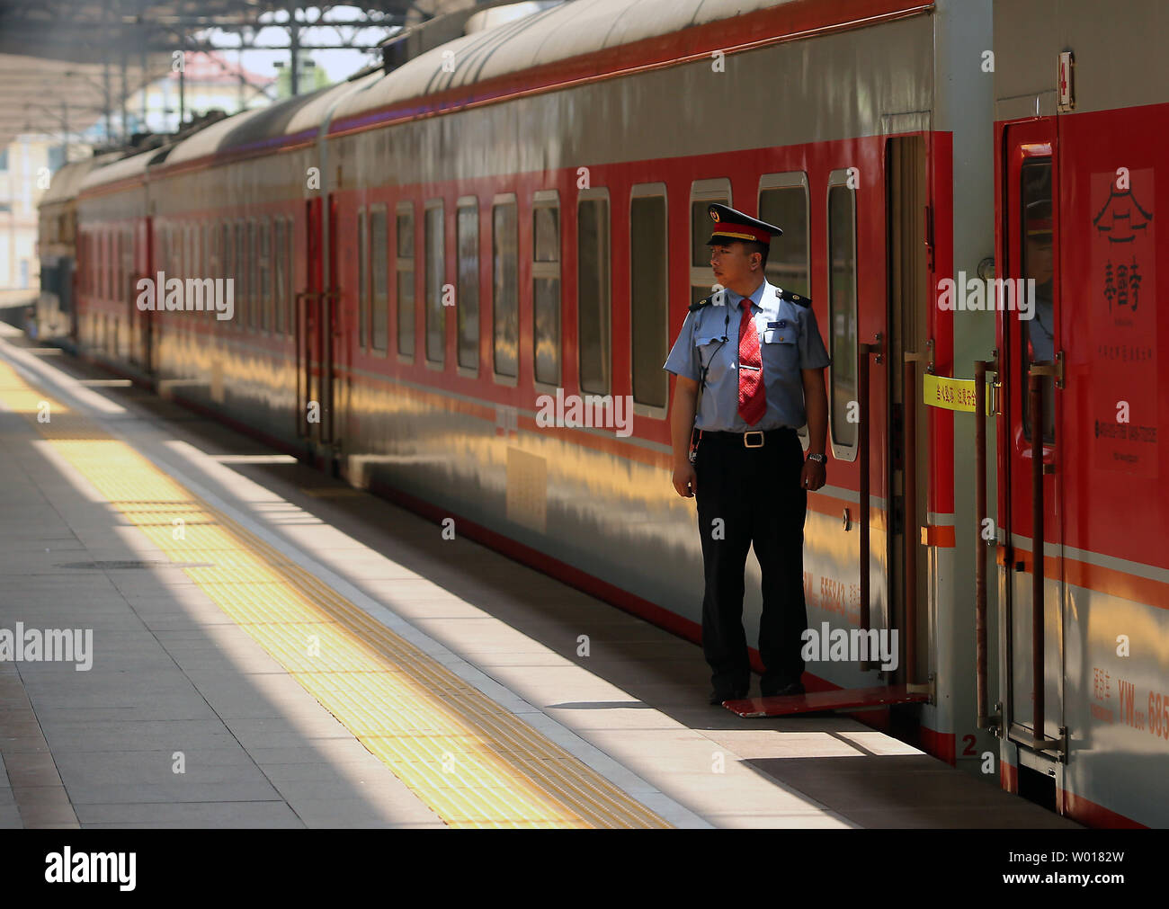 A Chinese train conductor waits at the entrance of a train carriage at ...