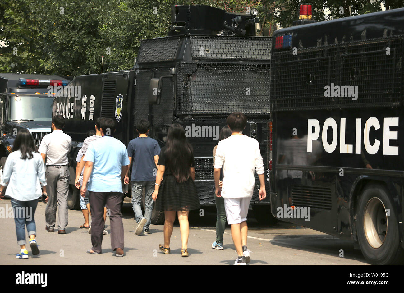 Chinese walk past a row of police riot vehicles parked in downtown ...