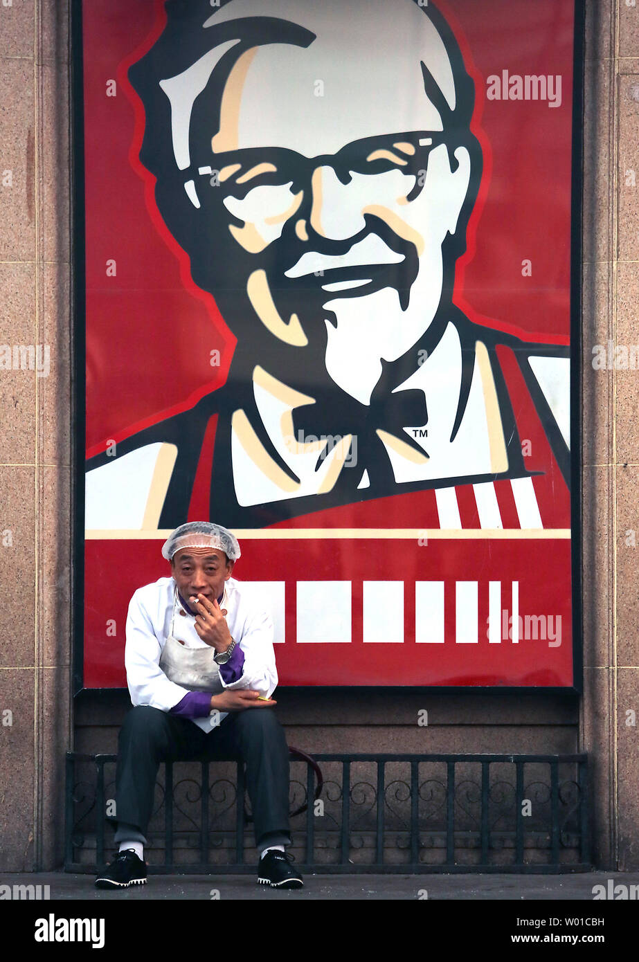 A Chinese cook smokes a cigarette outside a KFC at a bus station in ...