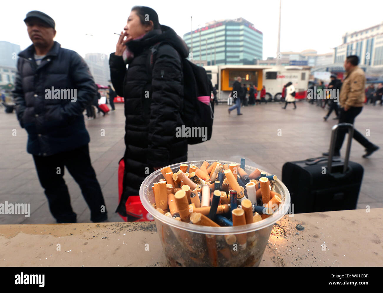 Chinese smoke cigarettes outside a bus terminal in Beijing on February ...