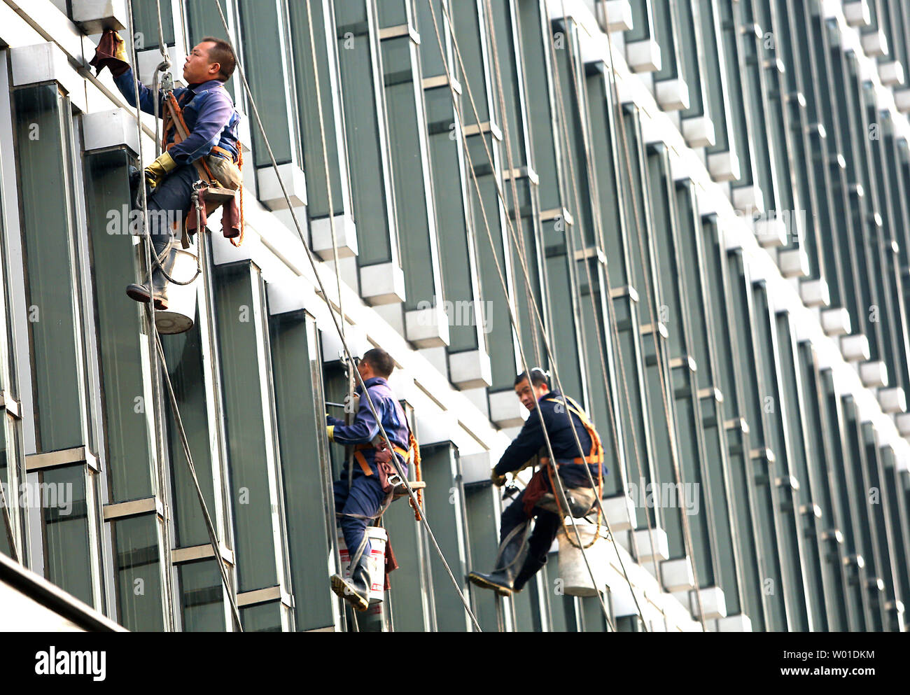 Chinese workers dangle on ropes and wooden planks as they clean the ...