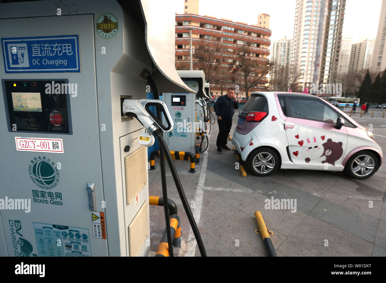 A Chinese man prepares to charge his electric car at a roadside ...