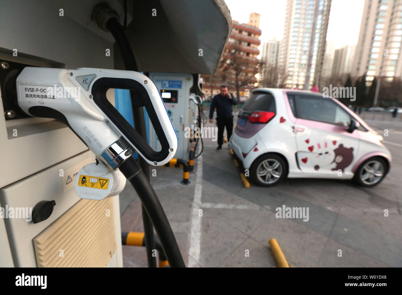 A Chinese man prepares to charge his electric car at a roadside ...