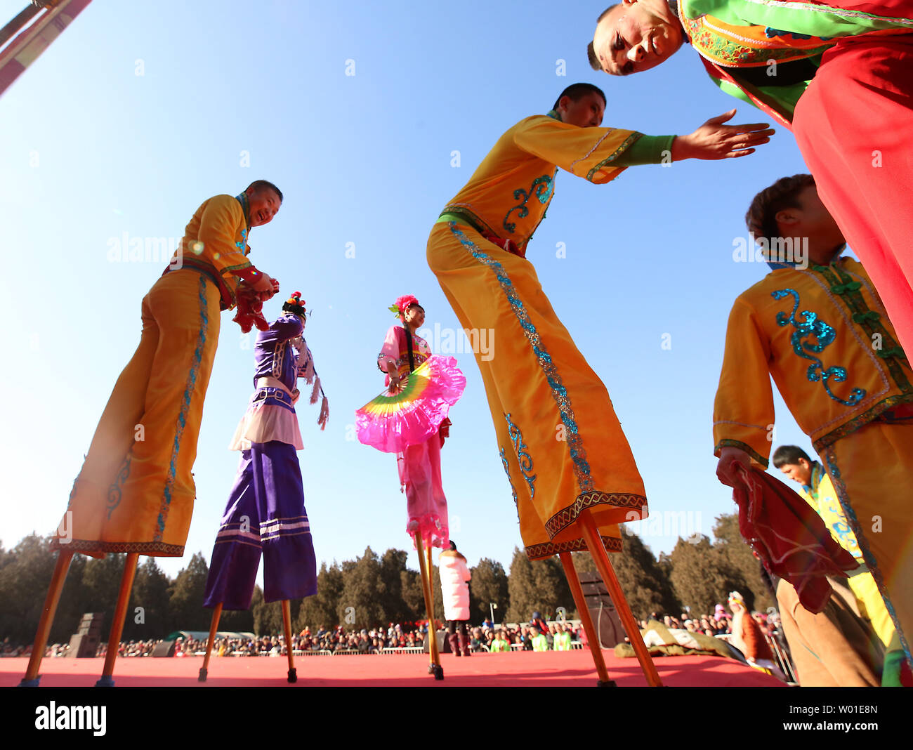 Chinese dancers on stilts wait to perform on an outdoor stage for a ...