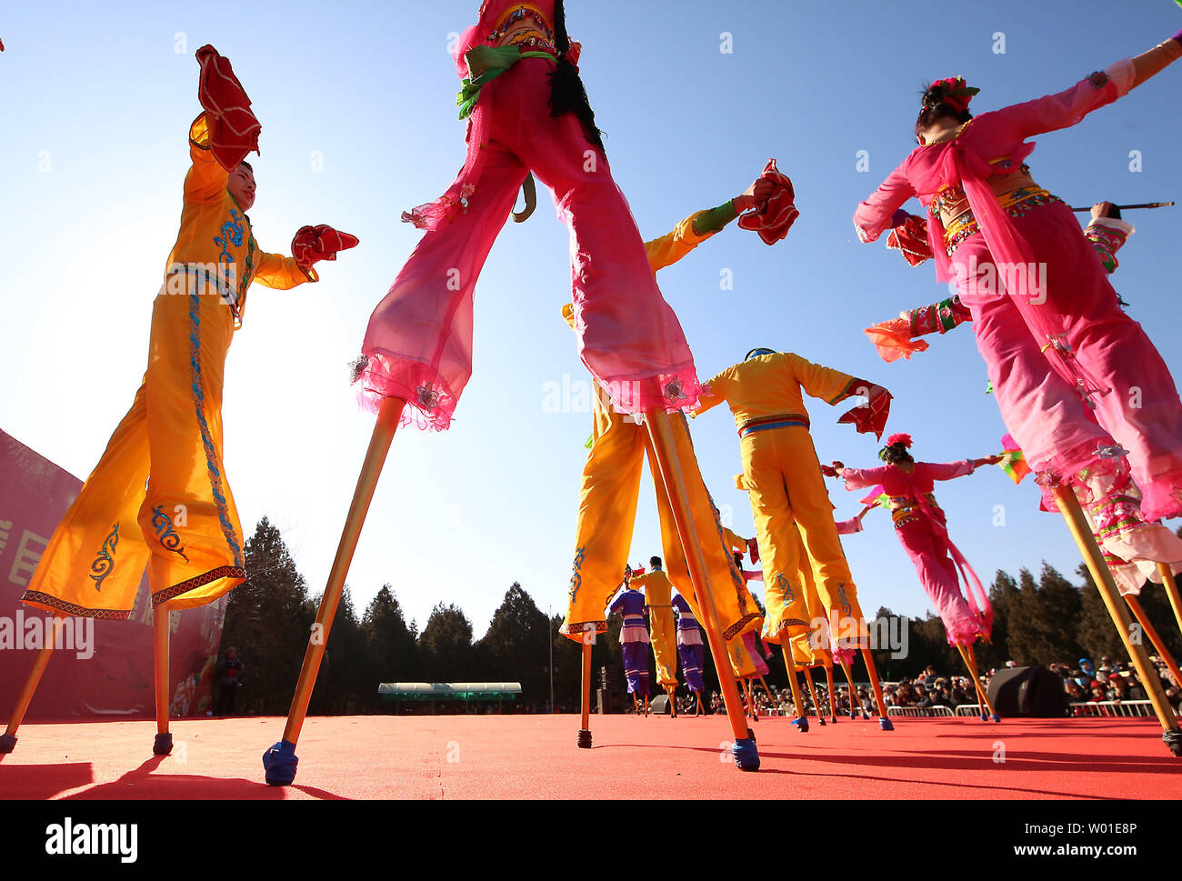 Chinese dancers on stilts perform on an outdoor stage for a large crowd ...