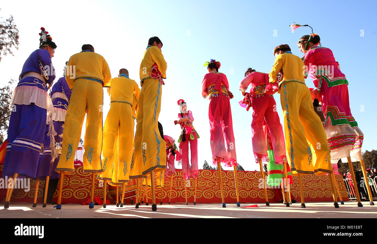 Chinese dancers on stilts wait to perform on an outdoor stage for a ...