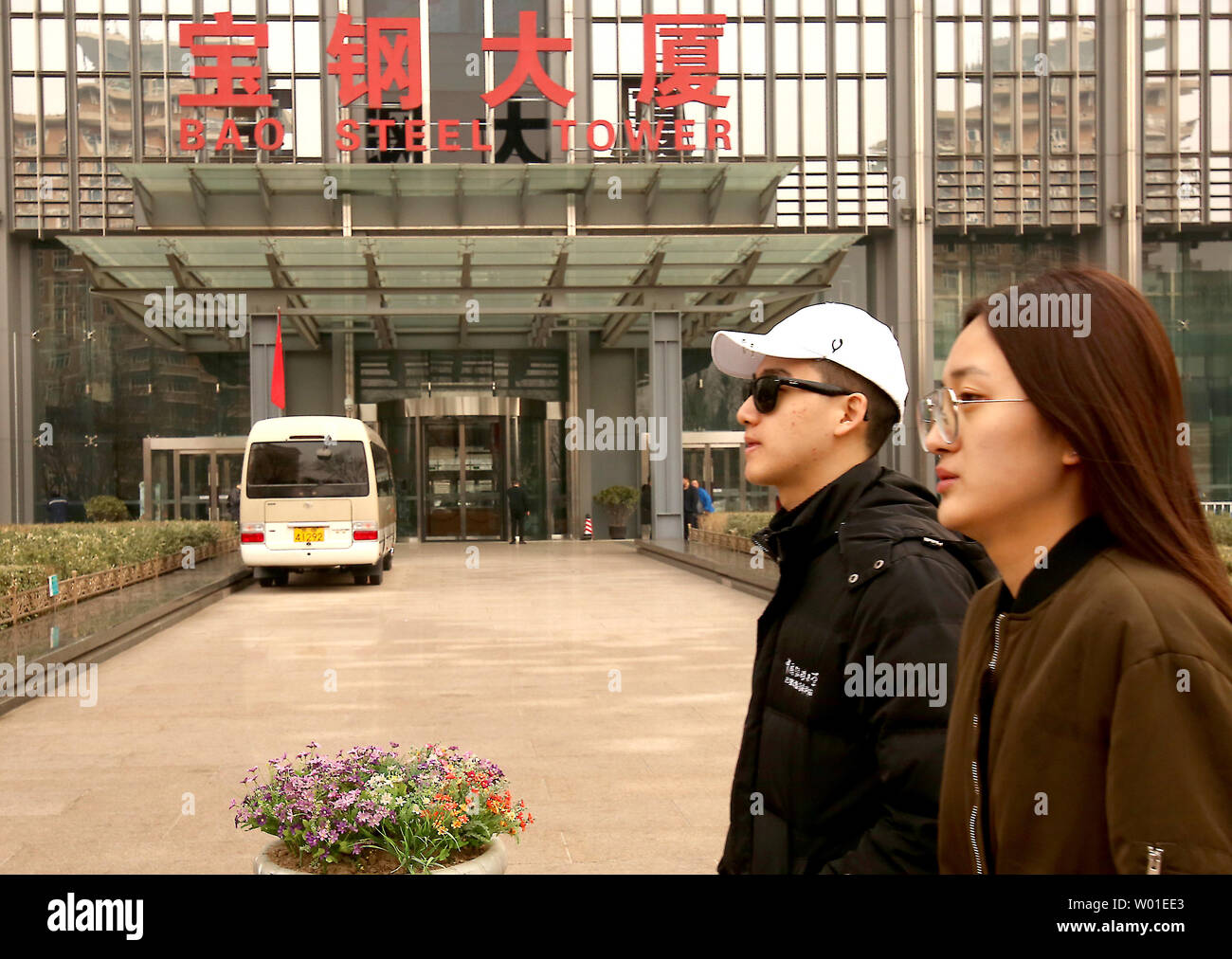Chinese walk past Bao Steel's headquarters in Beijing on March 12, 2018 ...