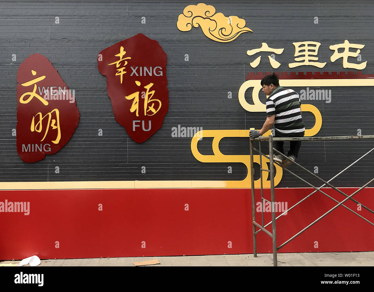 A Chinese worker puts the finishing touches on a public service sign ...