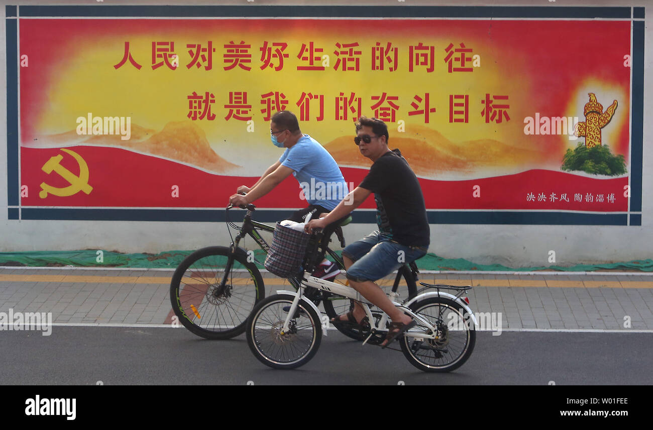 Chinese bike past a Communist Party public service announcement in ...