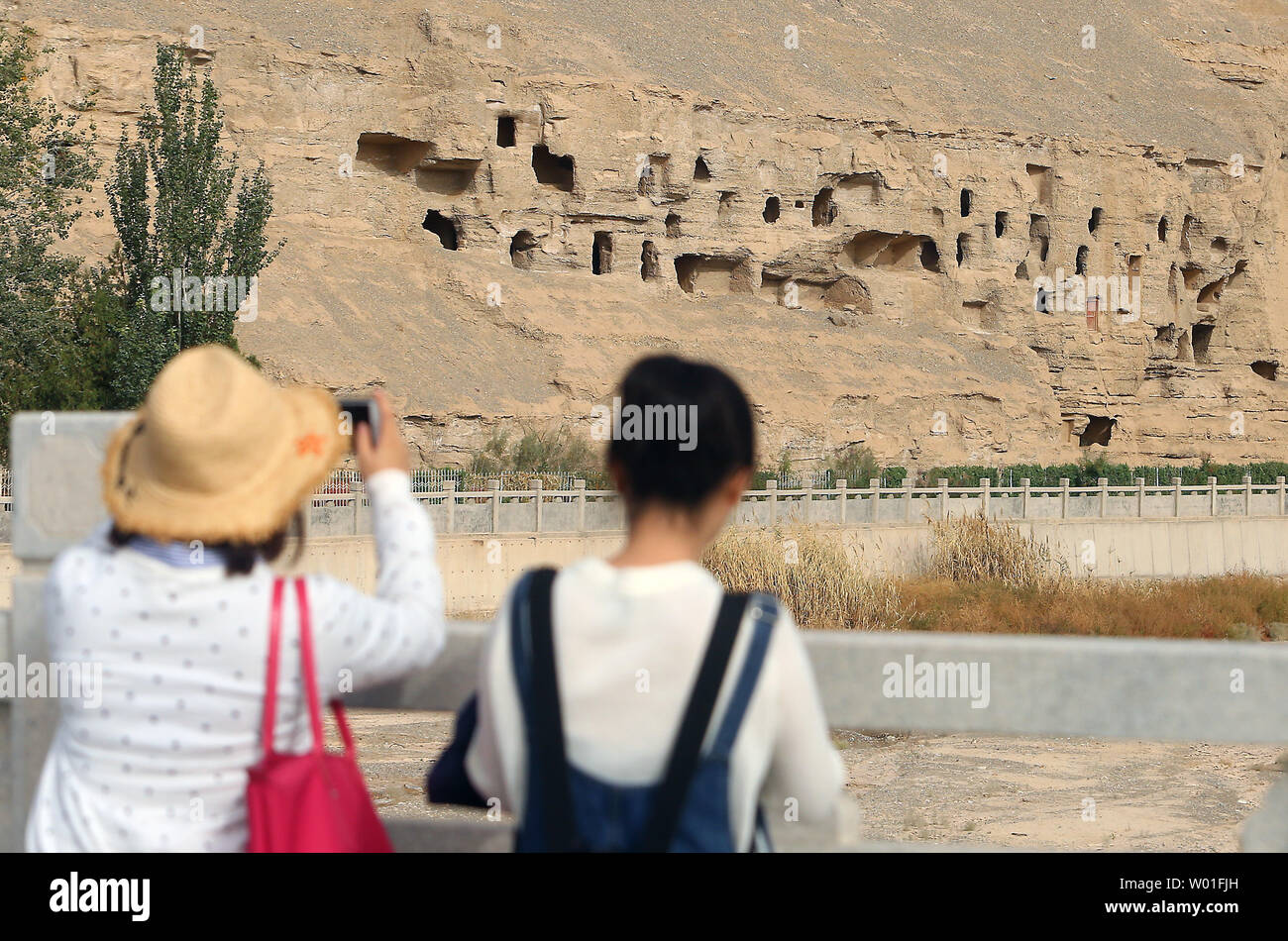Tourists visit the Magao Caves, also known as the Thousand Buddha ...