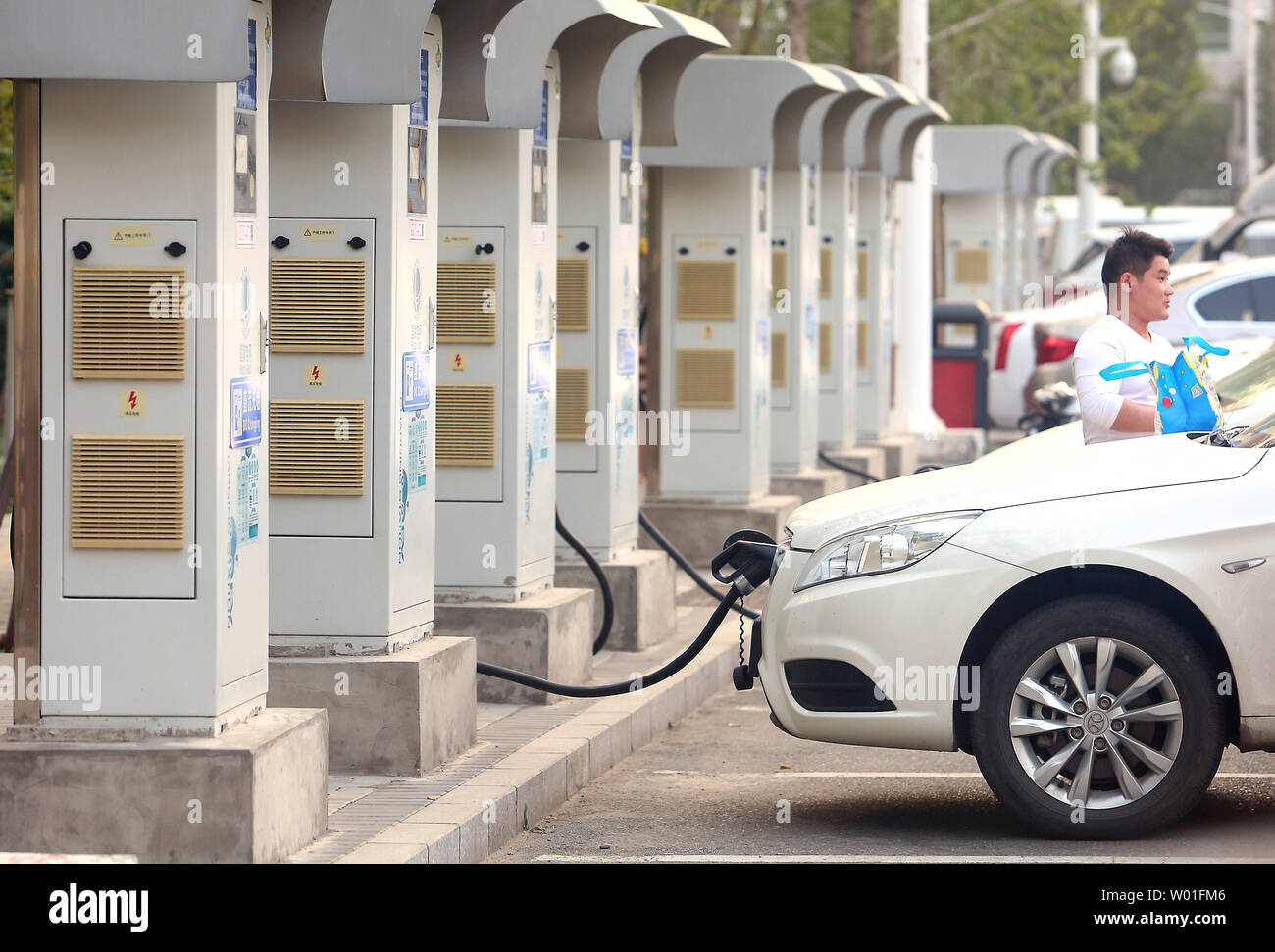 A Chinese man waits for his Chinese electronic vehicle (EV) to be ...