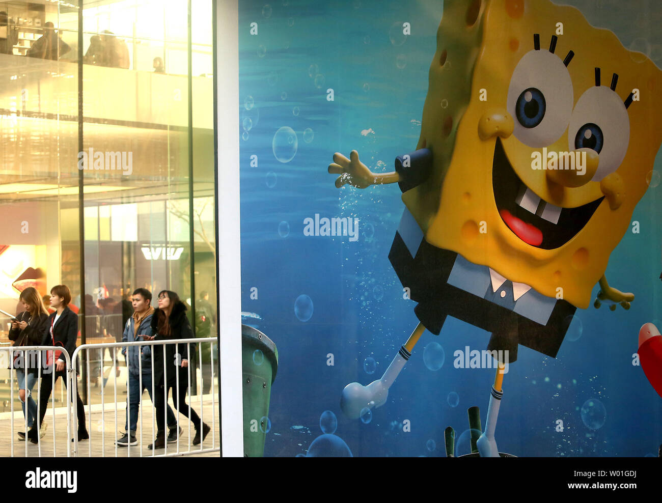 Chinese walk past a soon-to-open clothing store featuring designs of ...