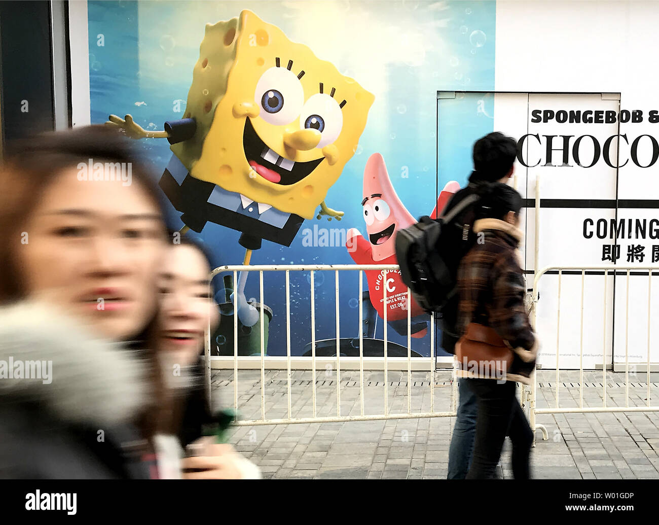 Chinese walk past a soon-to-open clothing store featuring designs of ...