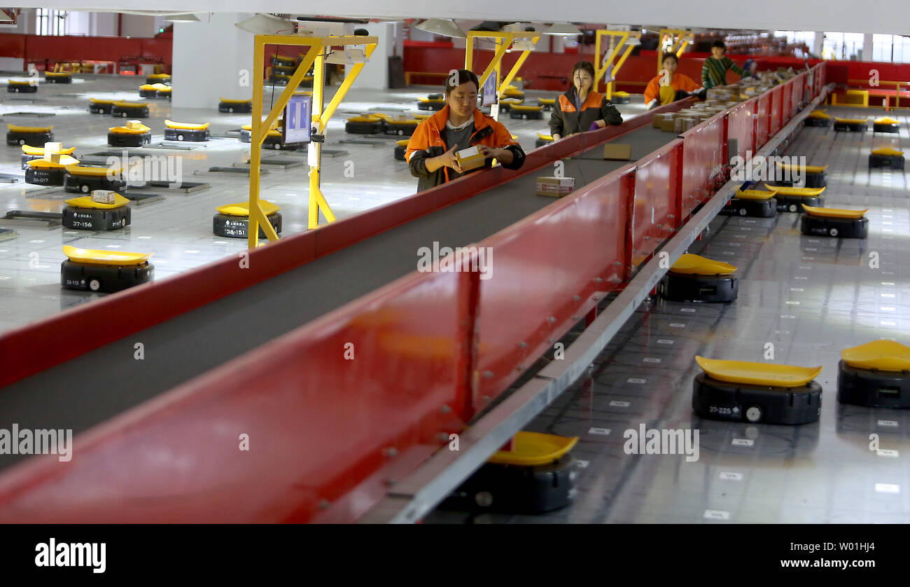 Workers monitor packages being sorted by small, automated guided ...