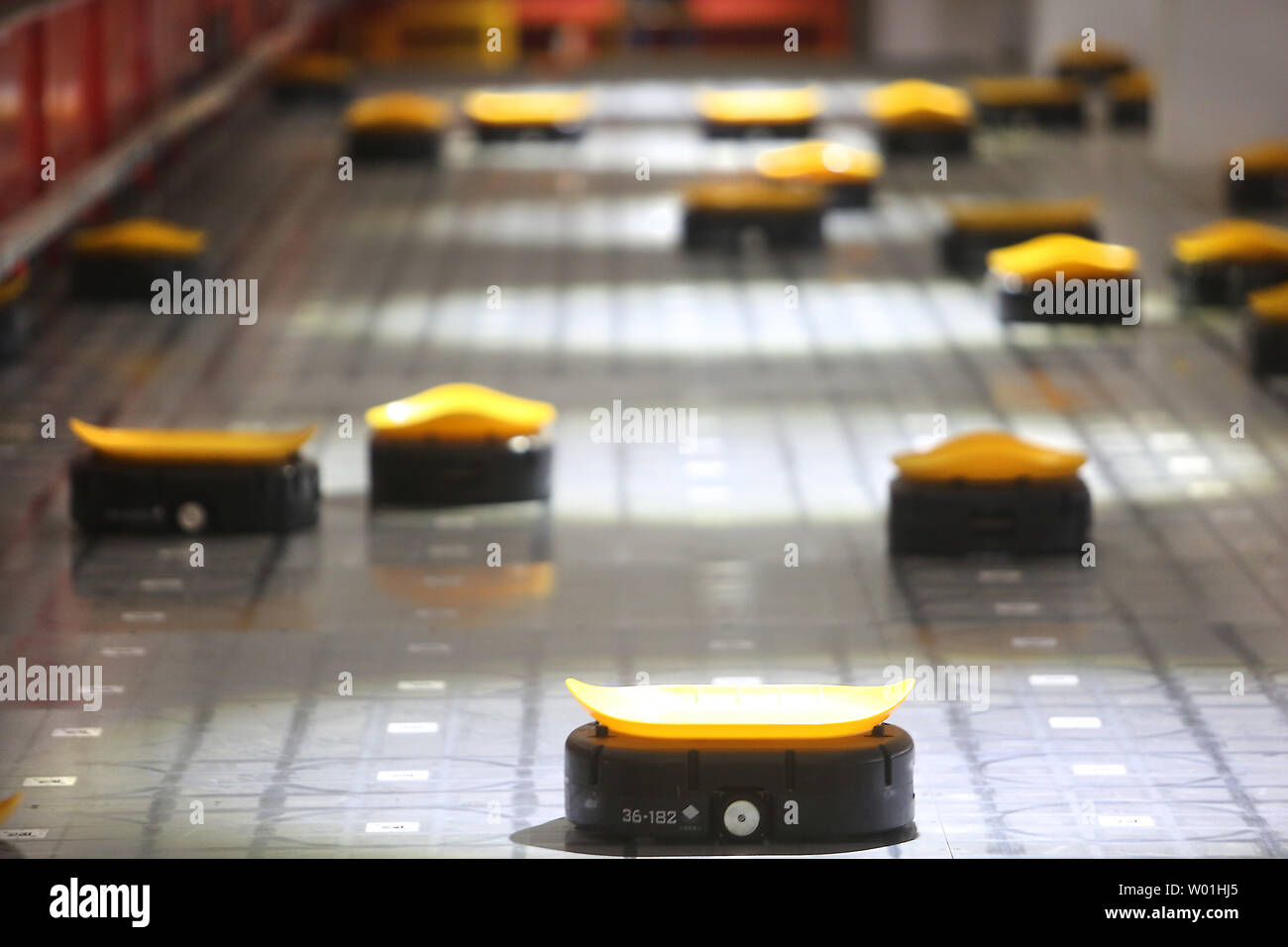 Workers monitor packages being sorted by small, automated guided ...