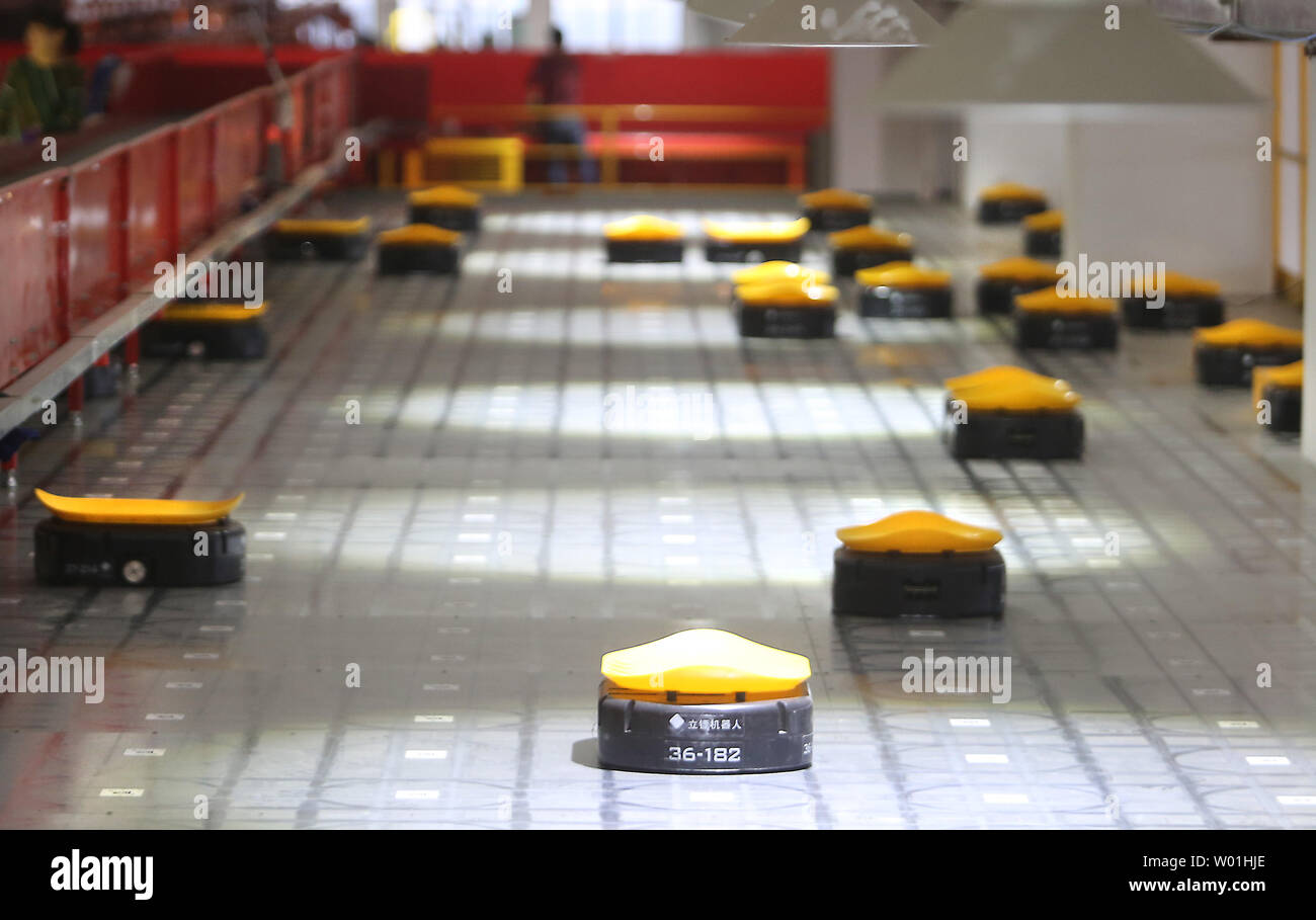 Workers monitor packages being sorted by small, automated guided ...