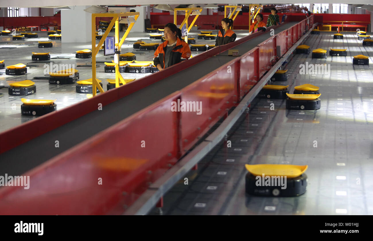 Workers monitor packages being sorted by small, automated guided ...